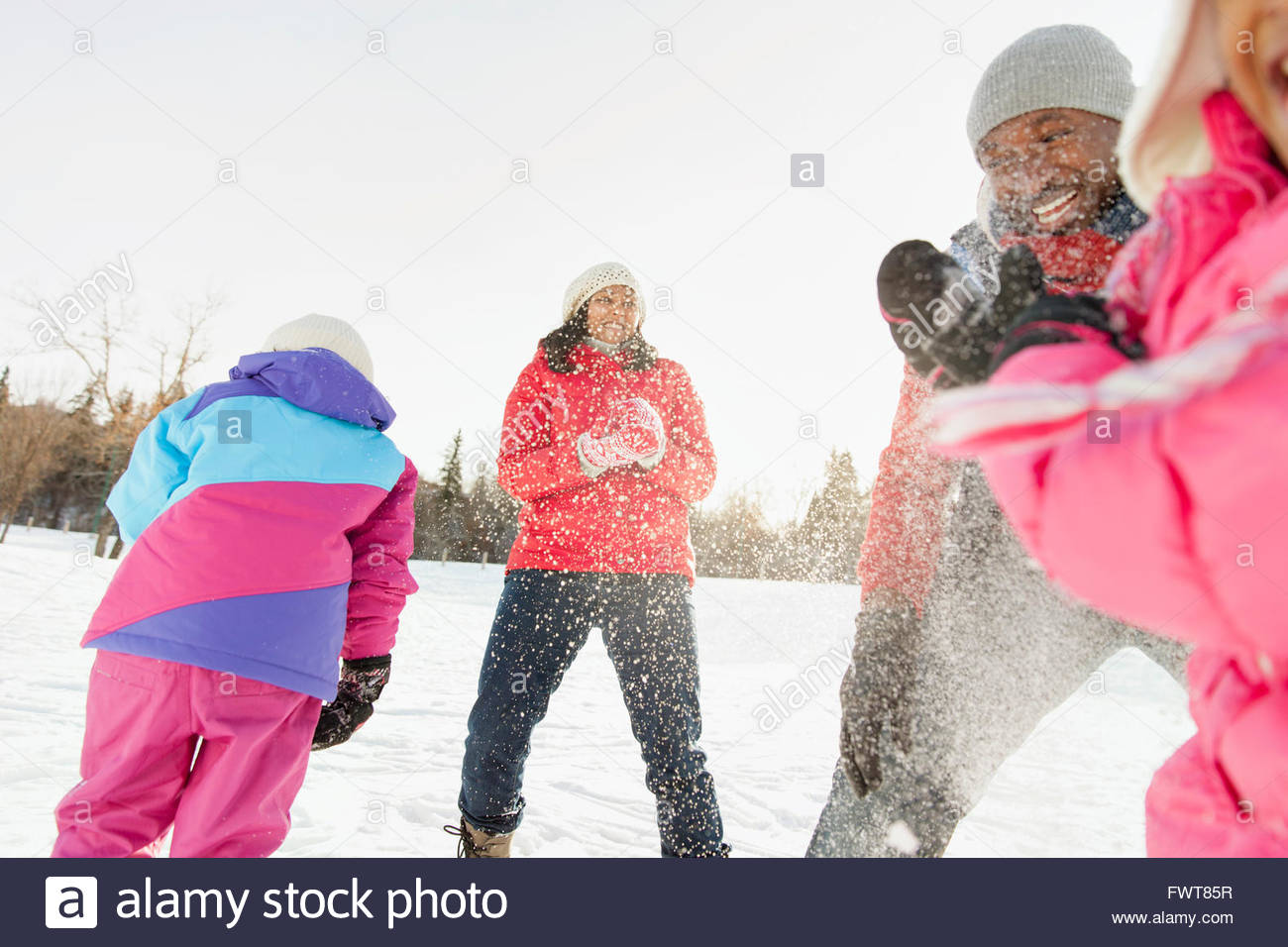 Happy family having a snow ball fight Stock Photo - Alamy