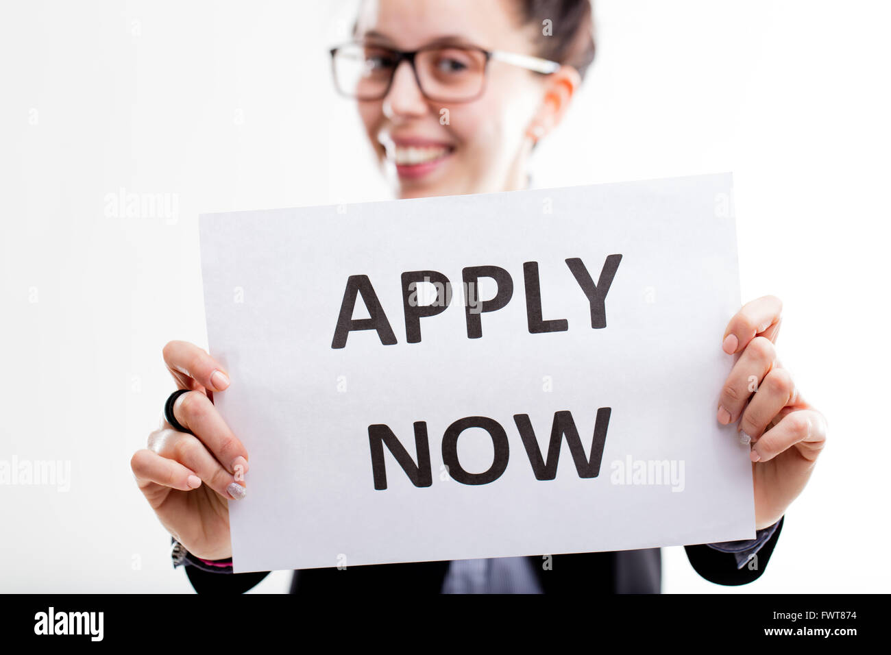 young smiling woman holding on an apply-now white sign in focus on the ...