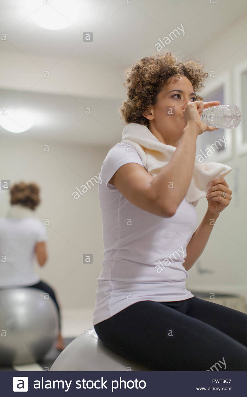 Woman drinking a bottle of water during workout Stock Photo - Alamy