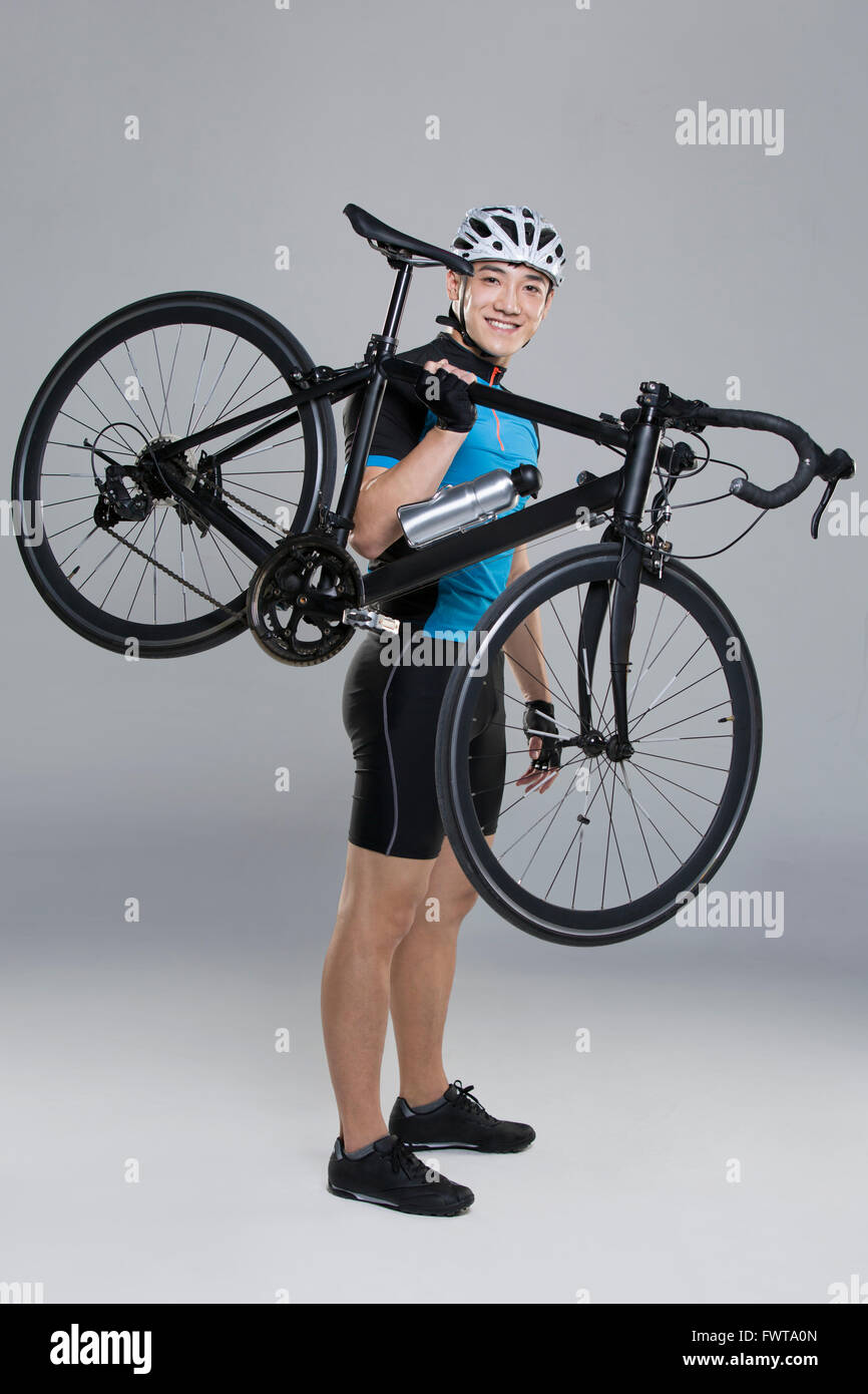 Young man carrying bicycle on shoulder Stock Photo - Alamy