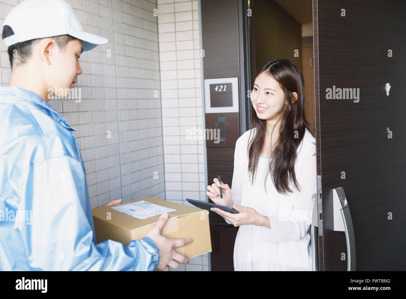 Young Japanese woman getting package from delivery man Stock Photo - Alamy