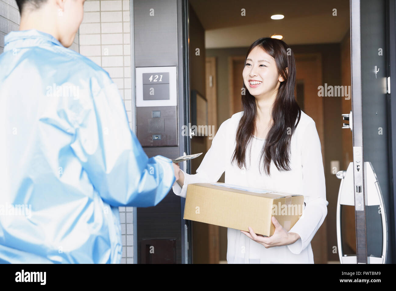 Young Japanese woman getting package from delivery man Stock Photo - Alamy