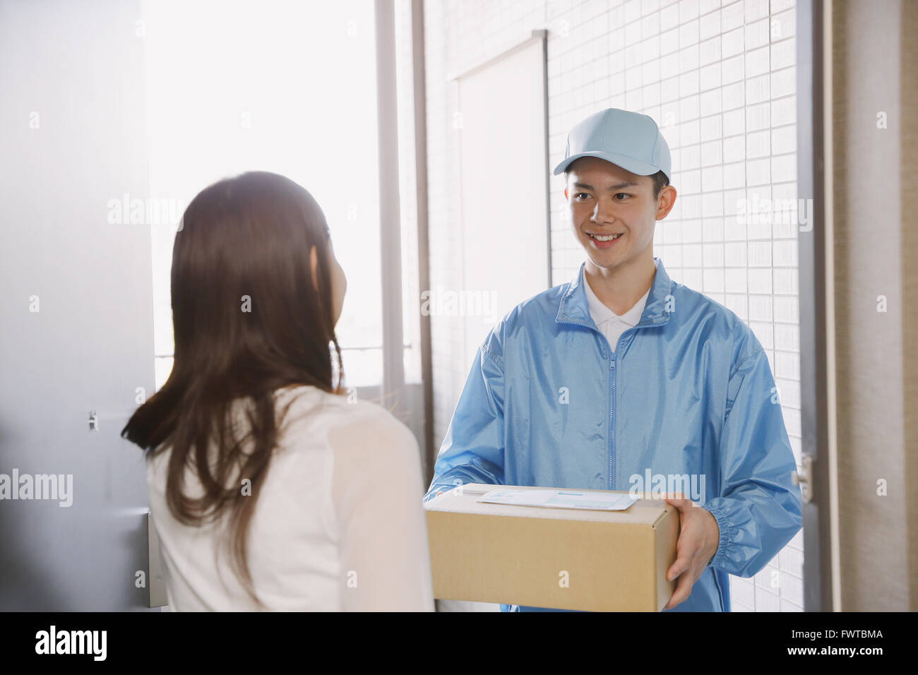 Young Japanese woman getting package from delivery man Stock Photo - Alamy