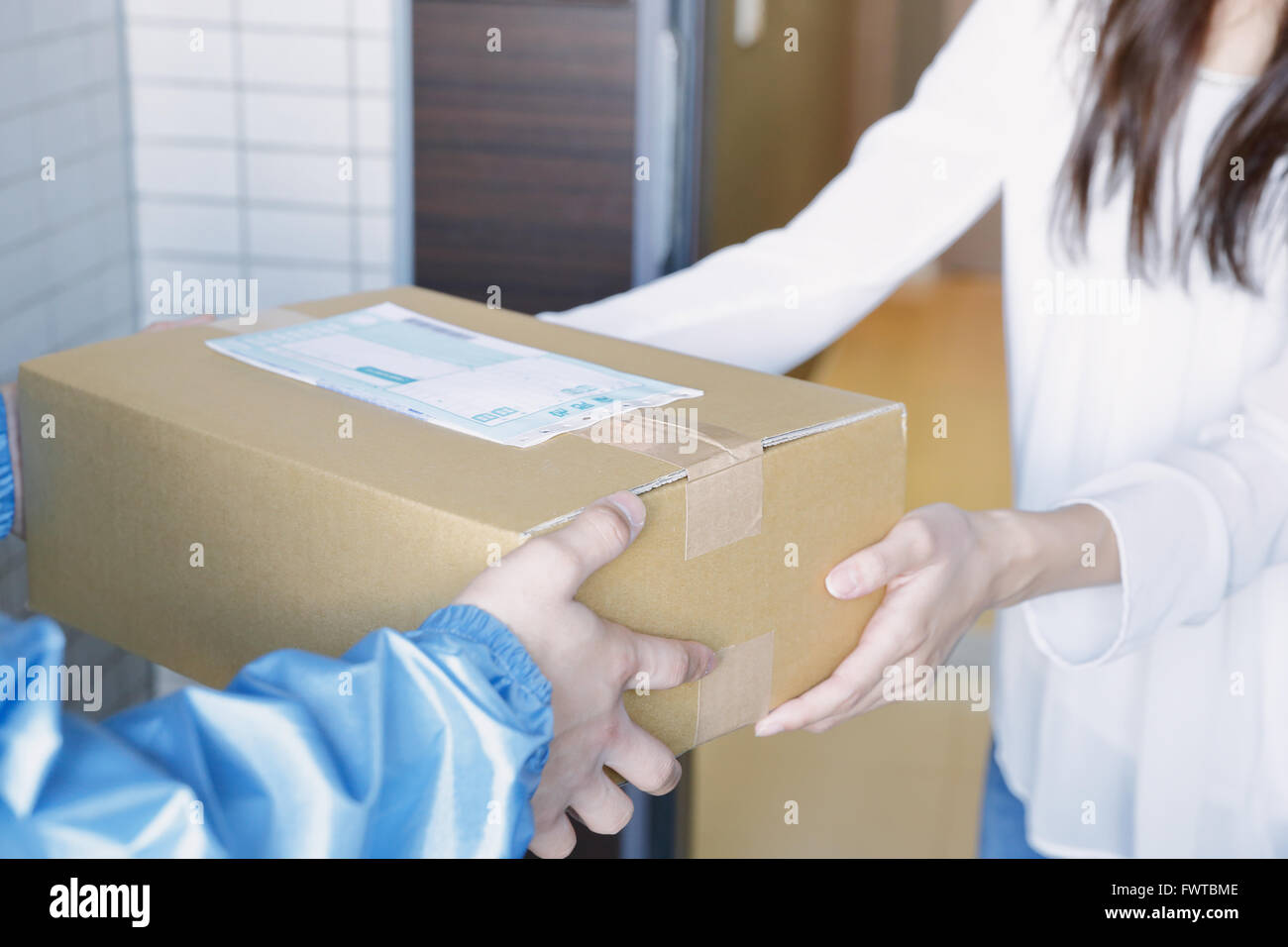 Young Japanese woman getting package from delivery man Stock Photo - Alamy