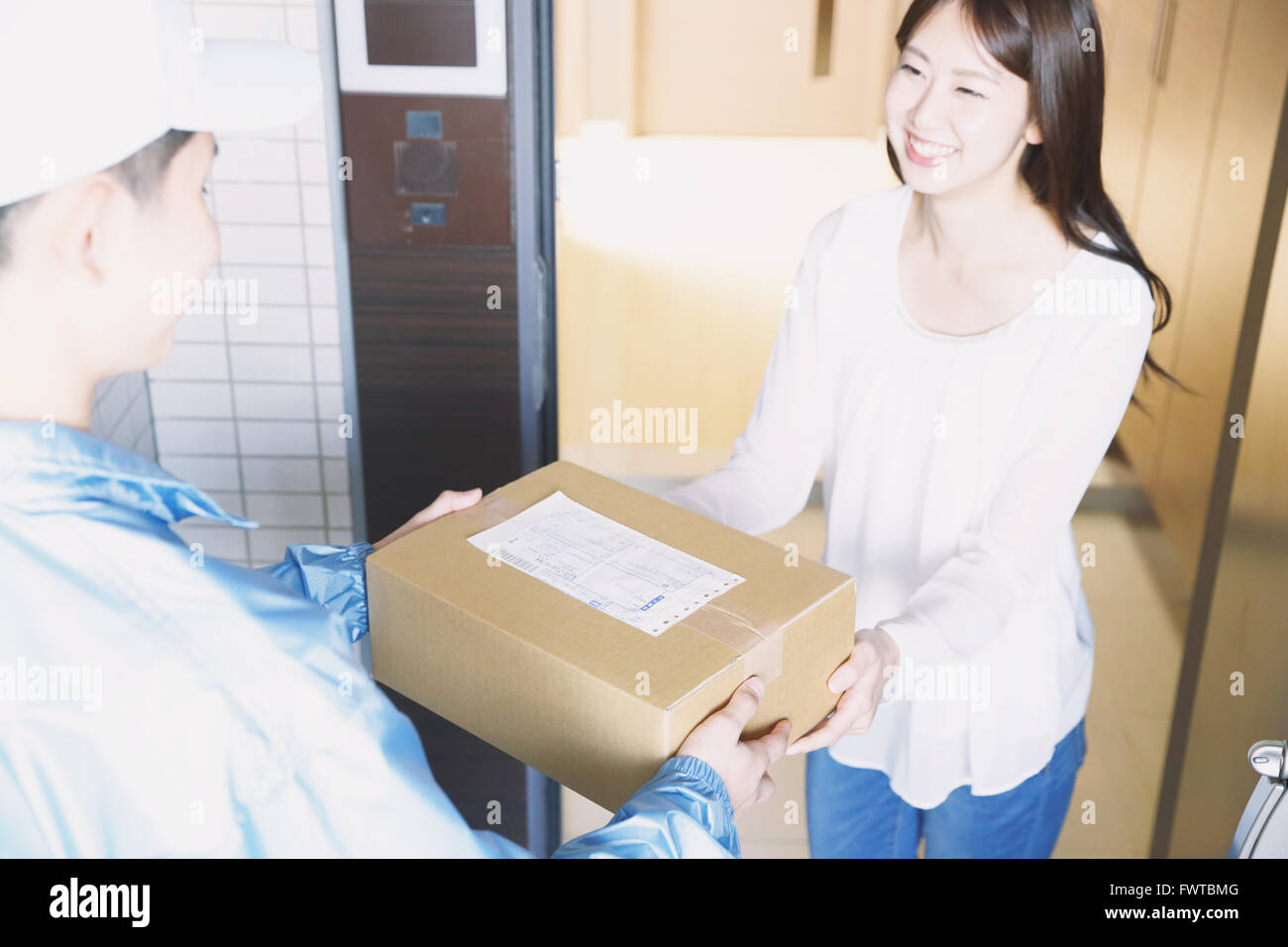 Young Japanese woman getting package from delivery man Stock Photo - Alamy
