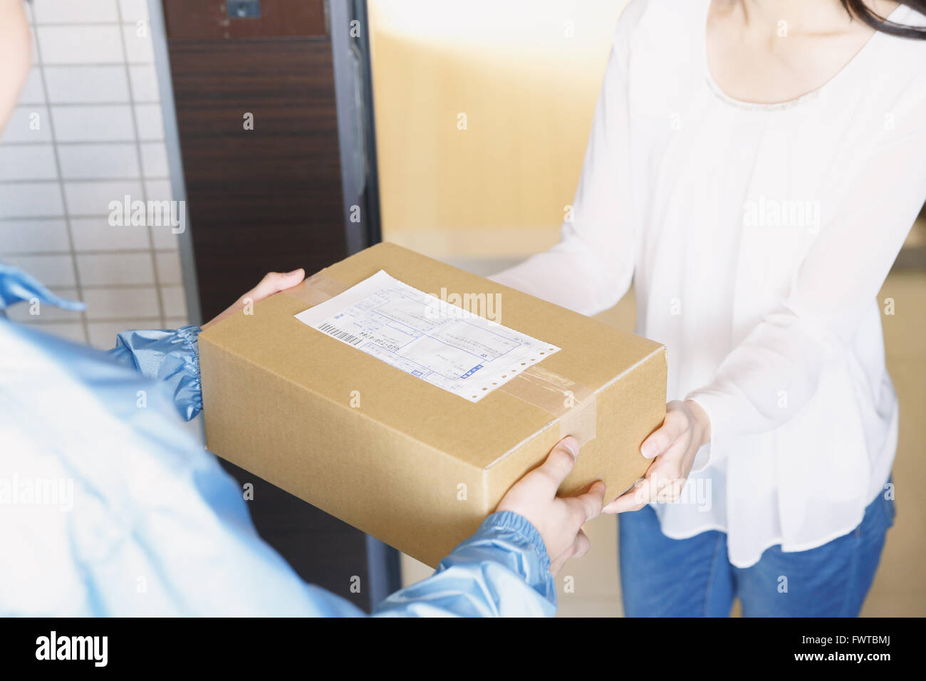 Young Japanese woman getting package from delivery man Stock Photo - Alamy