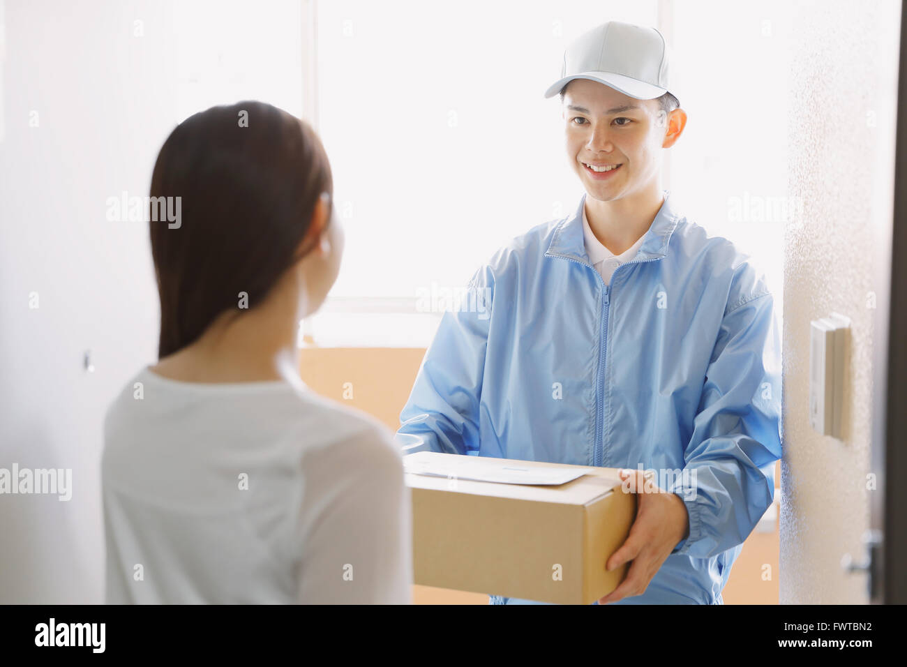 Young Japanese woman getting package from delivery man Stock Photo - Alamy