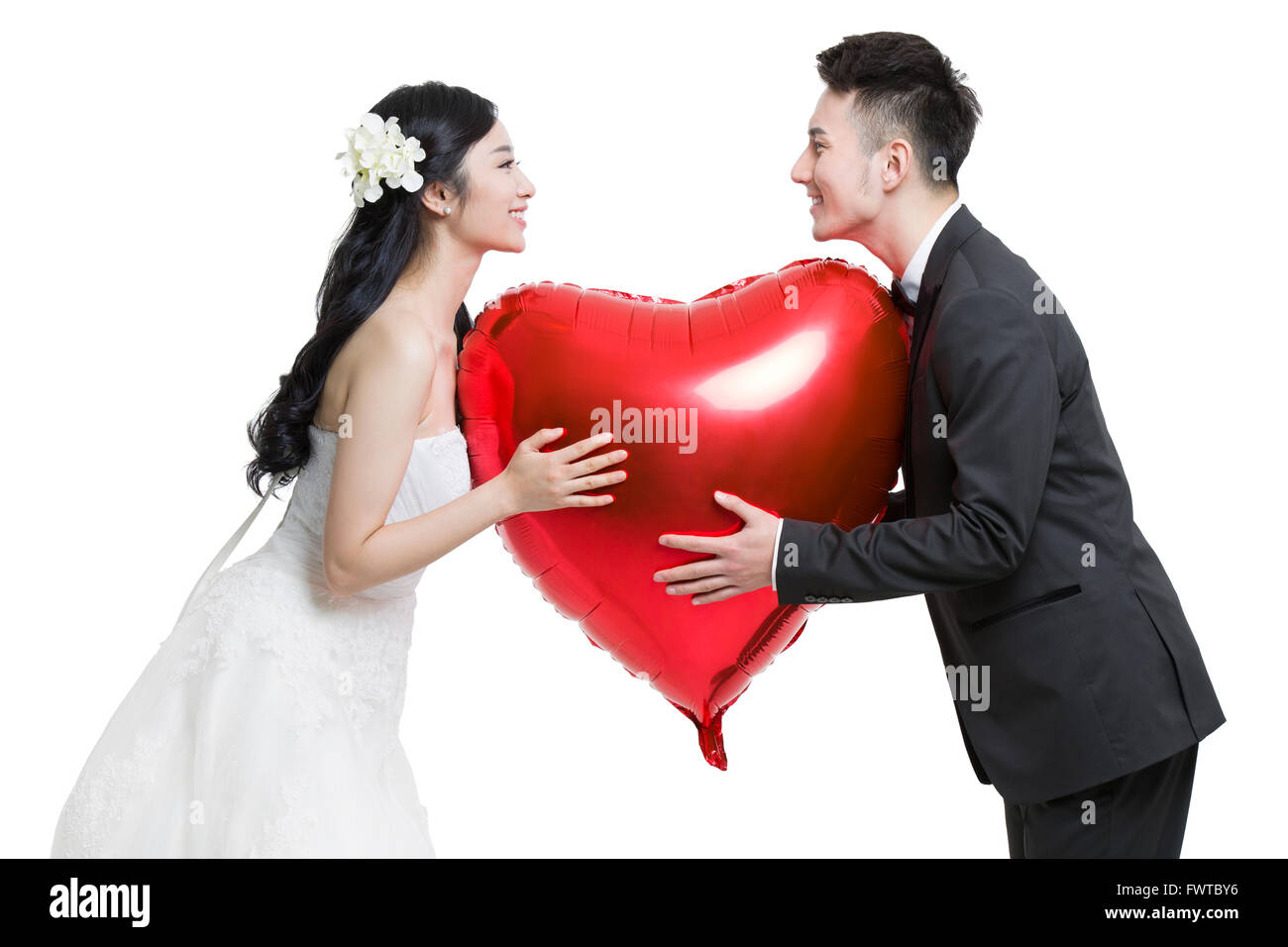 Happy bride and groom holding a heart-shaped balloon Stock Photo - Alamy