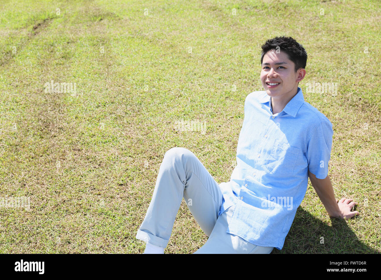 Young Japanese man sitting on grass Stock Photo - Alamy