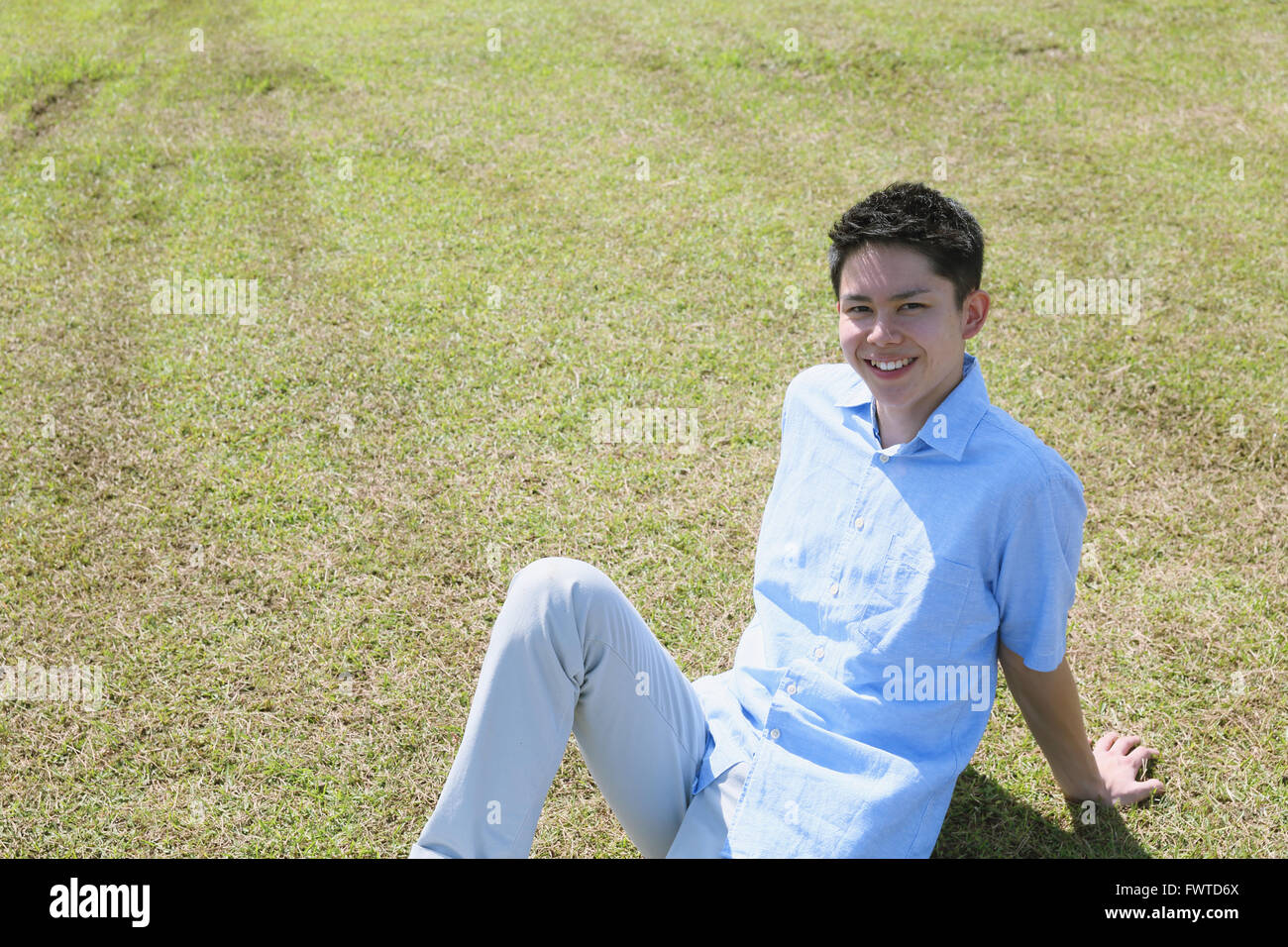 Young Japanese man sitting on grass Stock Photo - Alamy