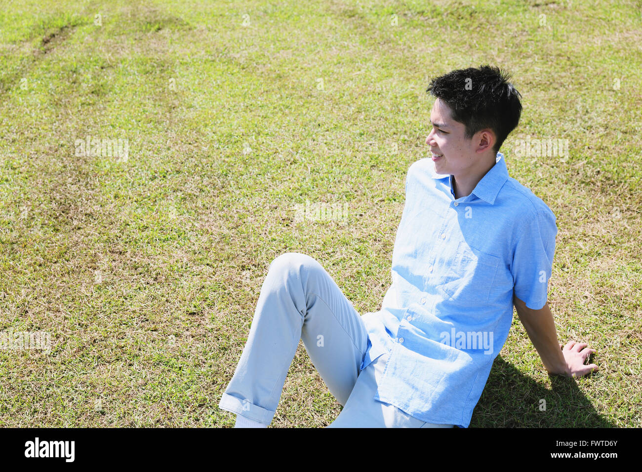 Young Japanese man sitting on grass Stock Photo - Alamy
