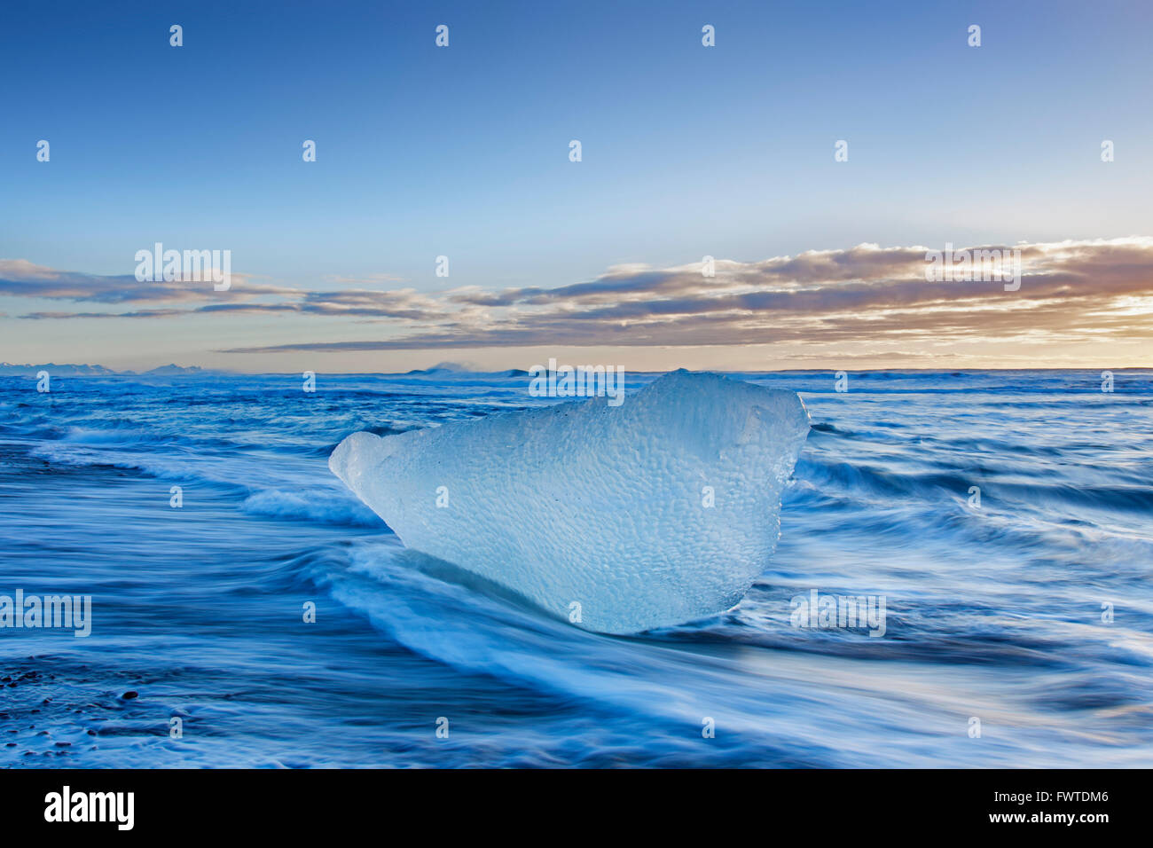 Melting block of ice washed on beach along the Atlantic Ocean coastline ...