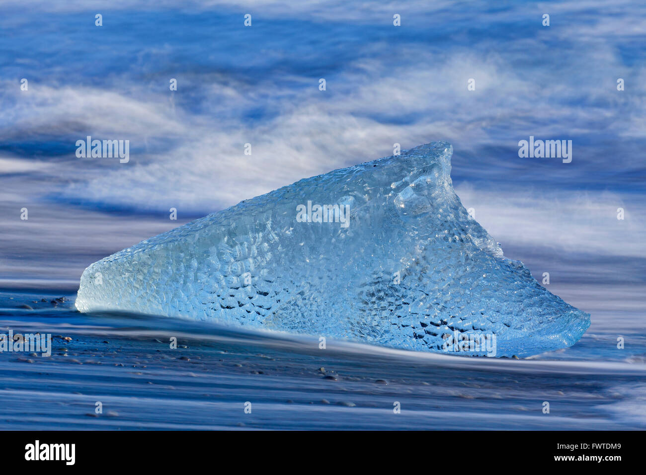 Melting block of ice washed on beach along the Atlantic Ocean coastline ...