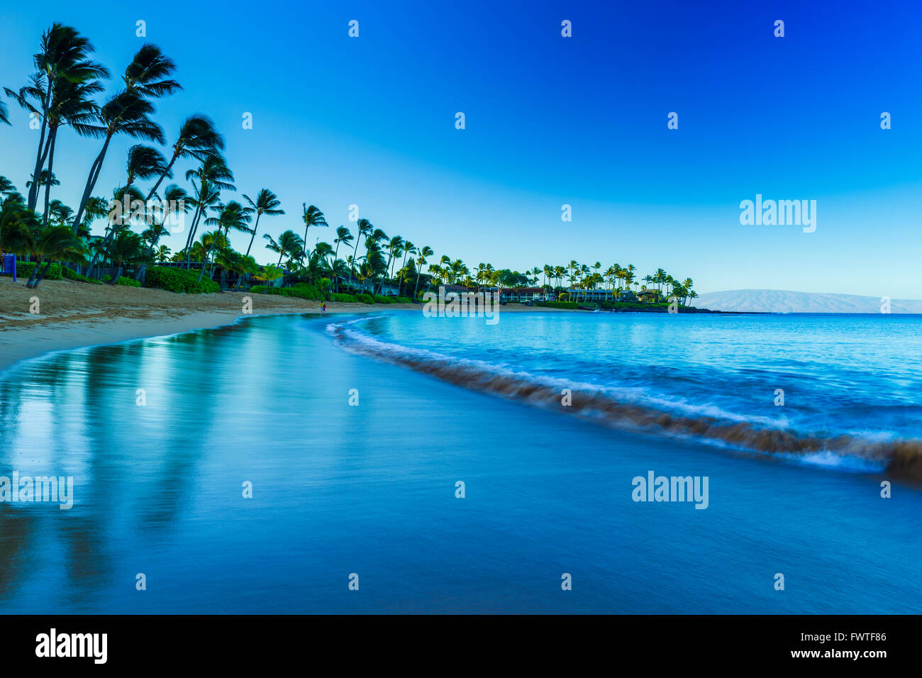 reflections on smooth wet sandy beach in front of resorts and beach in ...