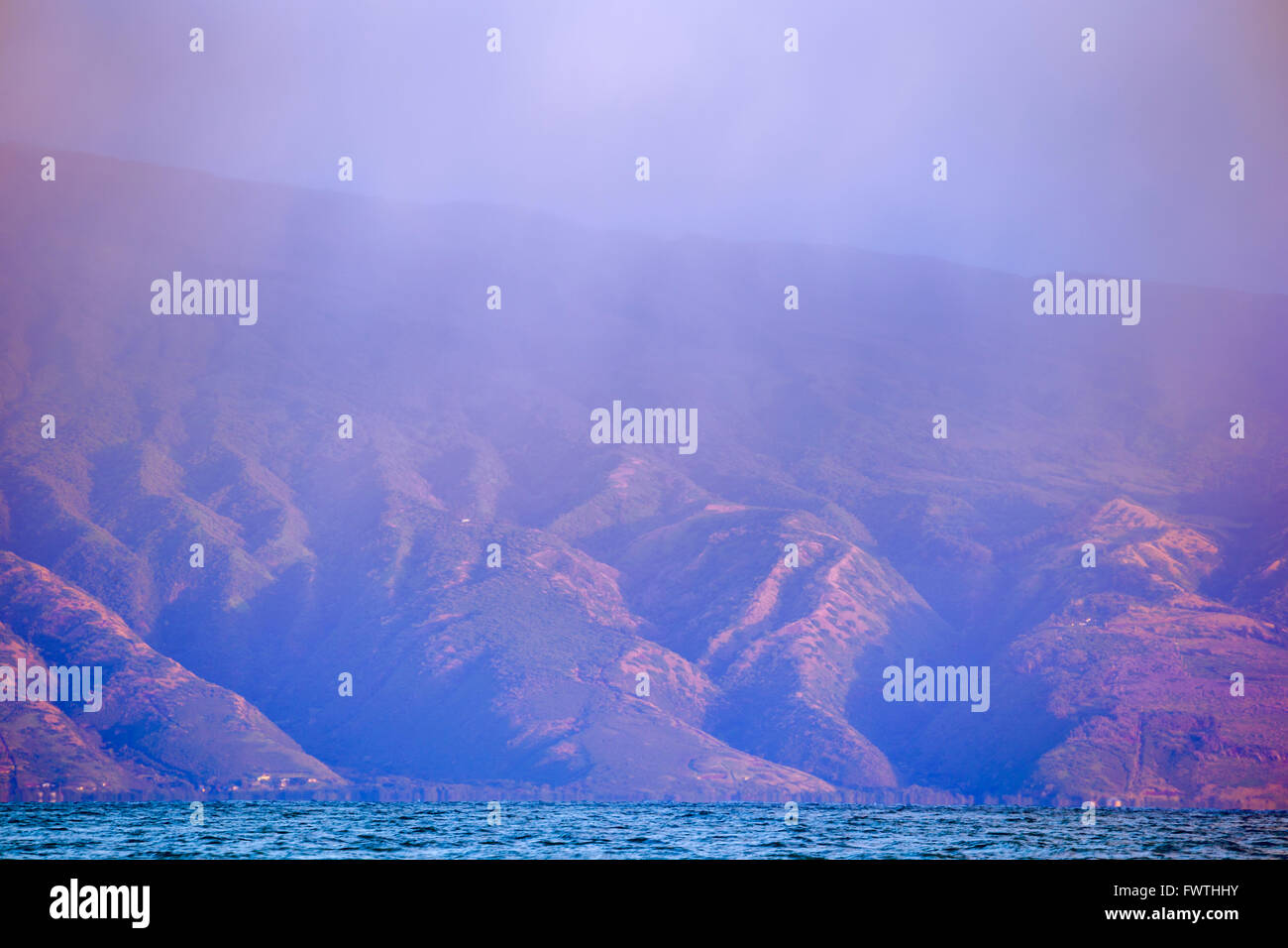Molokai with rain clouds at sunrise seen from Maui Stock Photo - Alamy