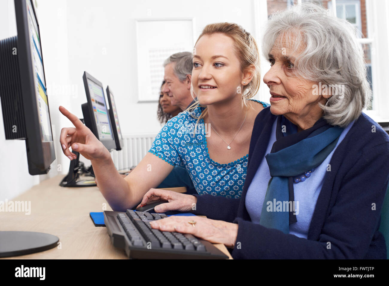 Tutor Helping Senior Woman In Computer Class Stock Photo - Alamy