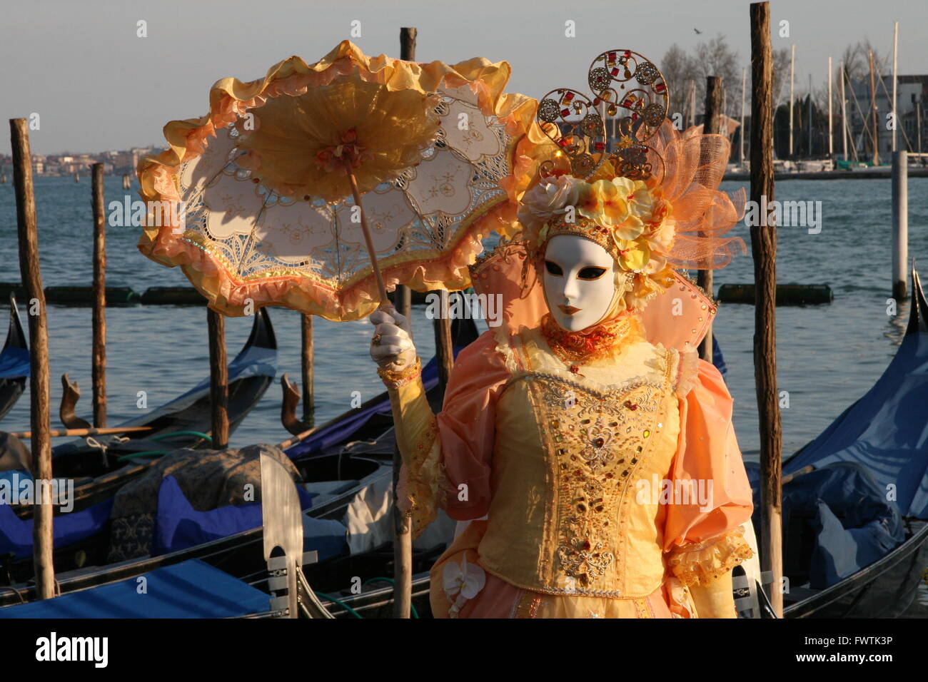 Masked carnival participant with backdrop of gondolas and the lagoon ...