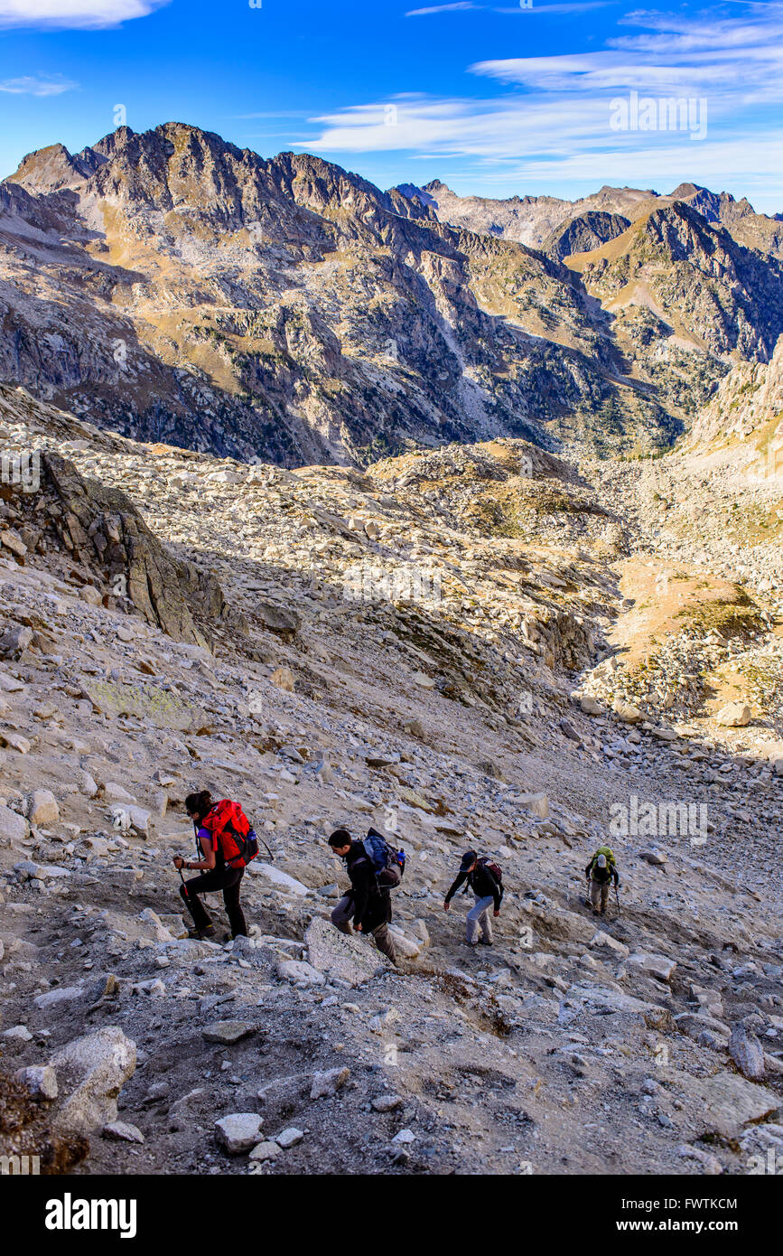 Four hikers climb up through the rocks with full backpacks Stock Photo ...