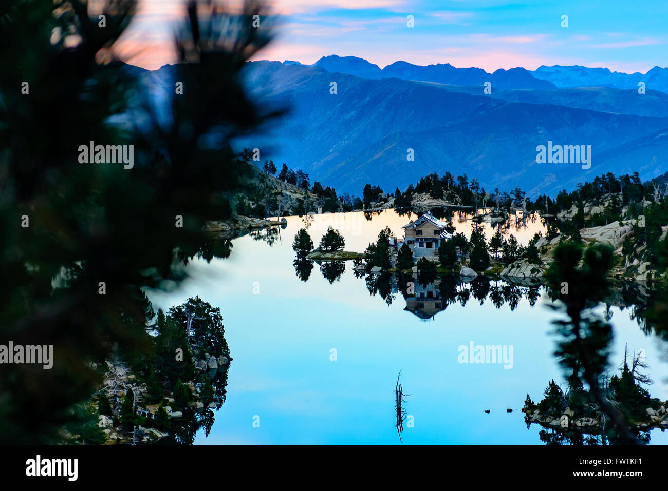 A mountain cabin is reflected in mirror like lake at the end of a ...