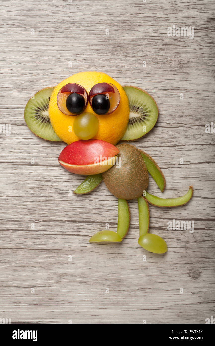 Funny ape made of apple and kiwi on wooden background Stock Photo - Alamy