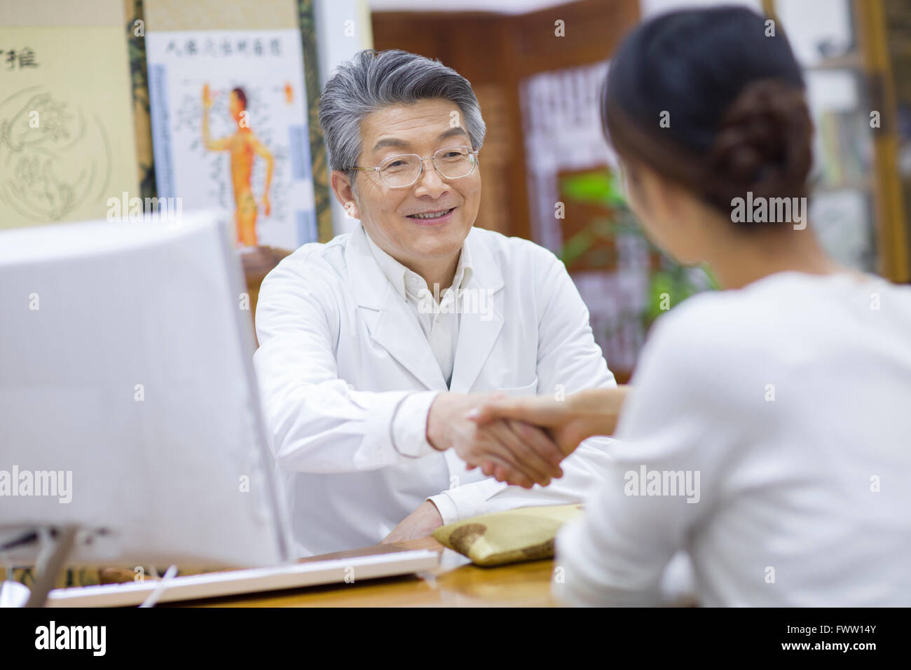Senior Chinese doctor shaking hands with patient Stock Photo - Alamy