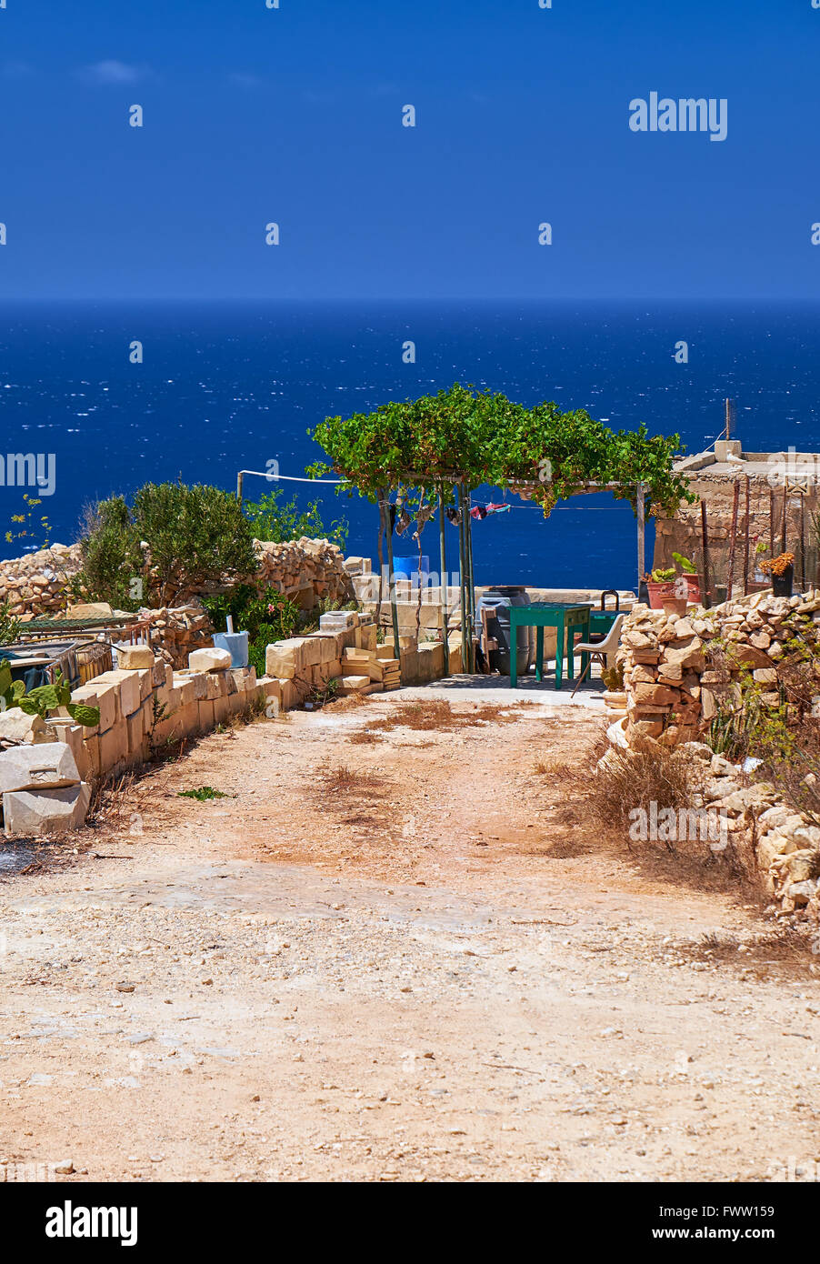Old maltese bungalow yard with stone fence and vine-covered canopy on ...