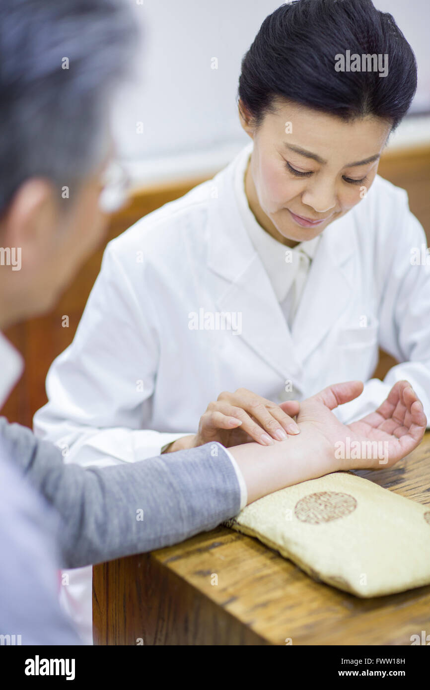 Female Chinese doctor taking the pulse of patient Stock Photo - Alamy