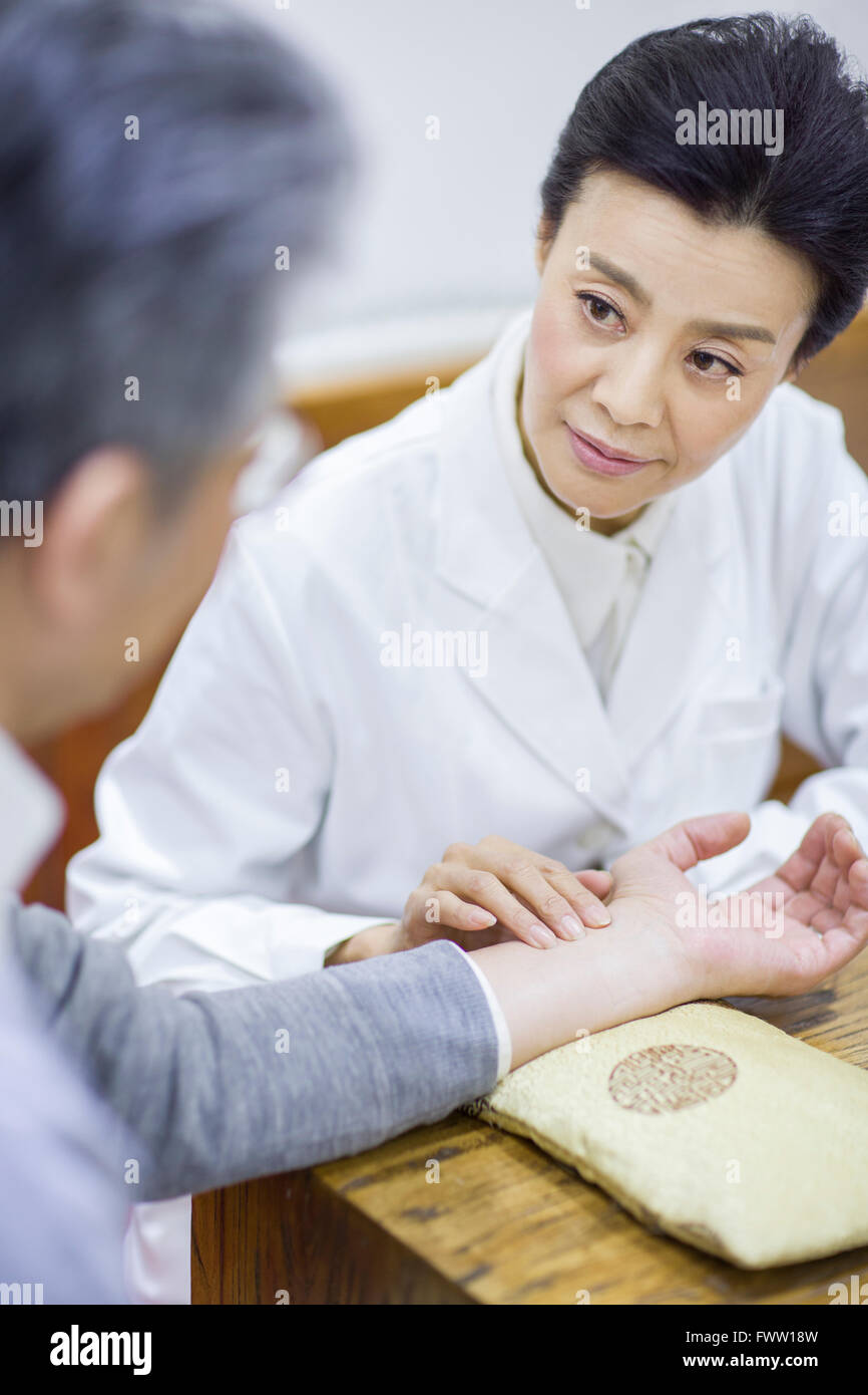 Female Chinese doctor taking the pulse of patient Stock Photo - Alamy