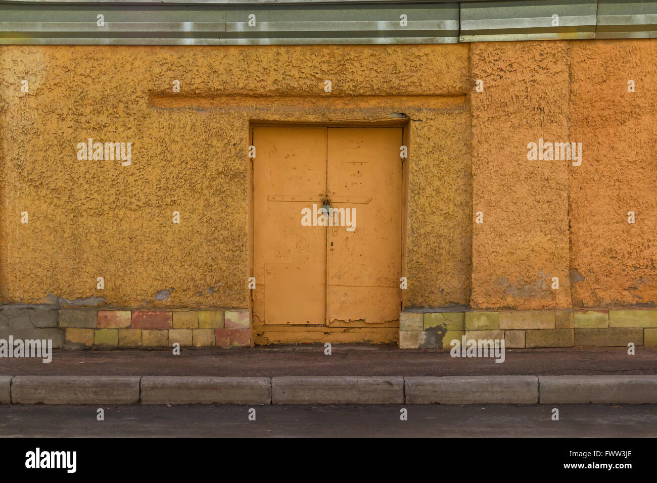 Locked iron door in yellow concrete wall front view Stock Photo - Alamy