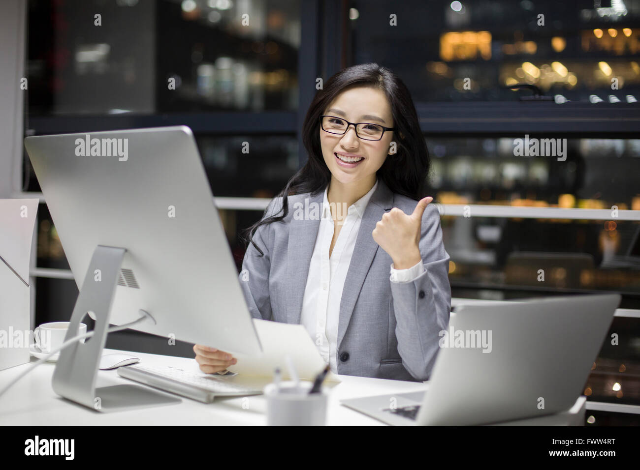 Happy businesswoman working late in office Stock Photo - Alamy