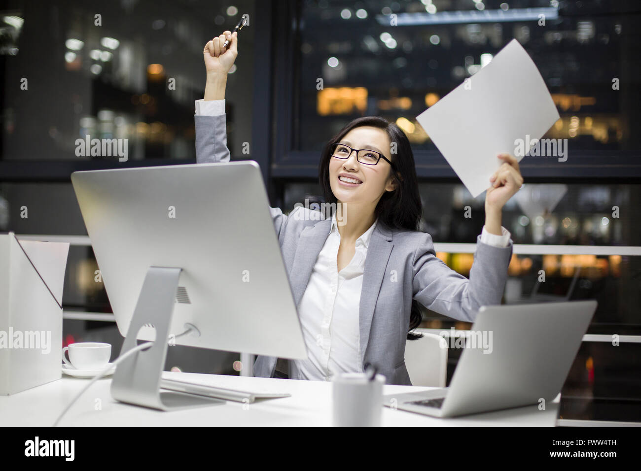 Happy businesswoman working late in office Stock Photo - Alamy