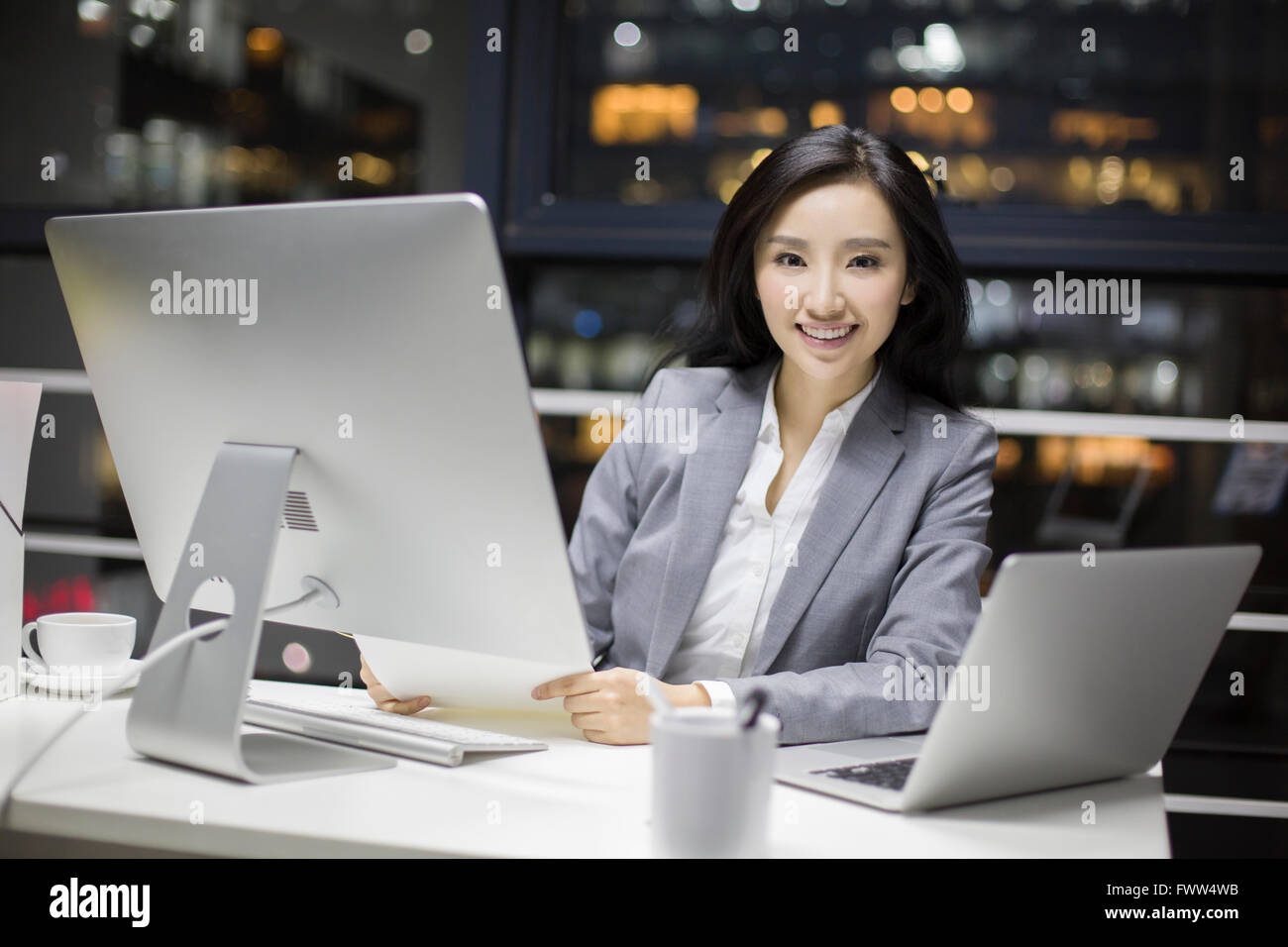 Happy businesswoman working late in office Stock Photo - Alamy