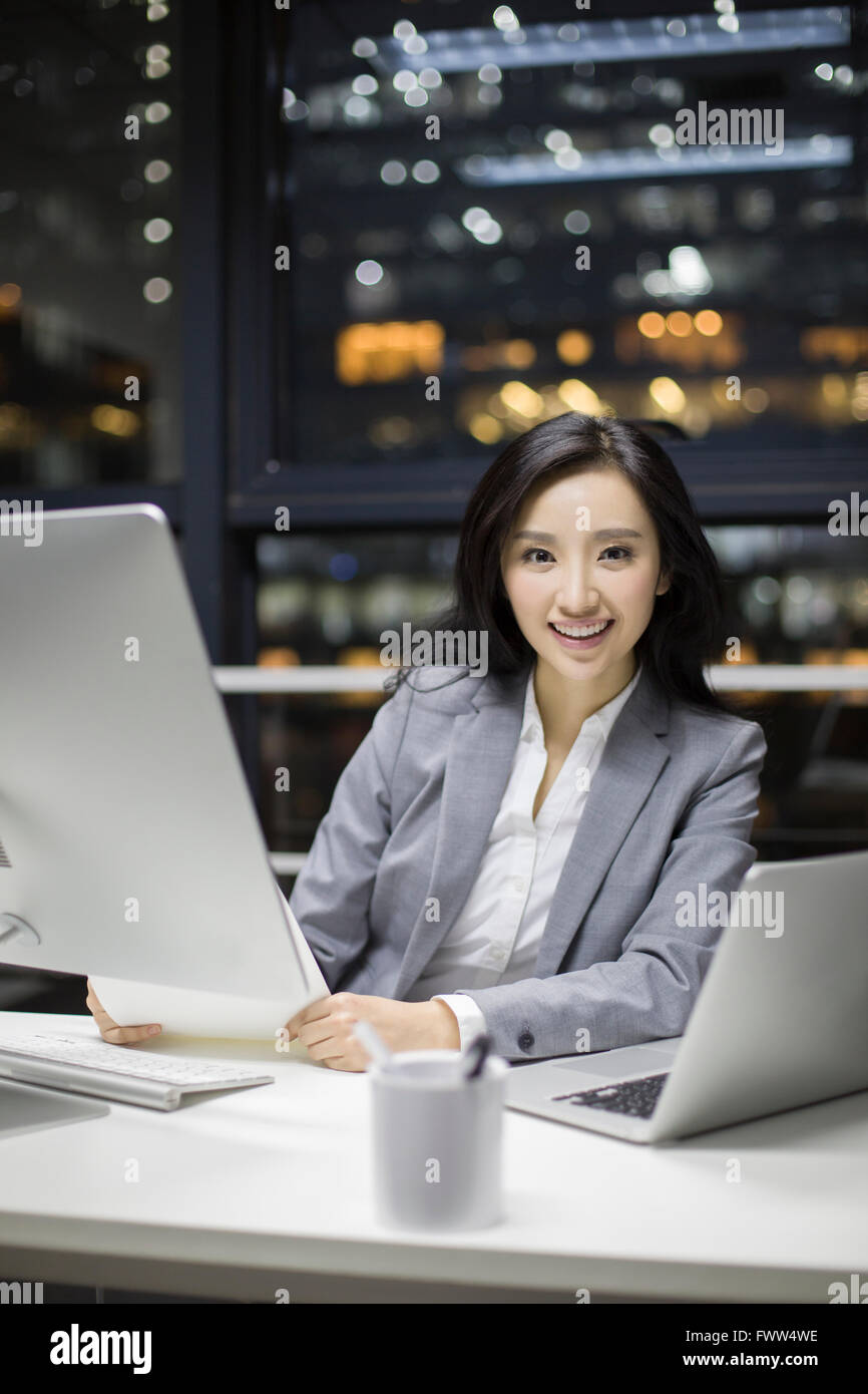 Happy businesswoman working late in office Stock Photo - Alamy
