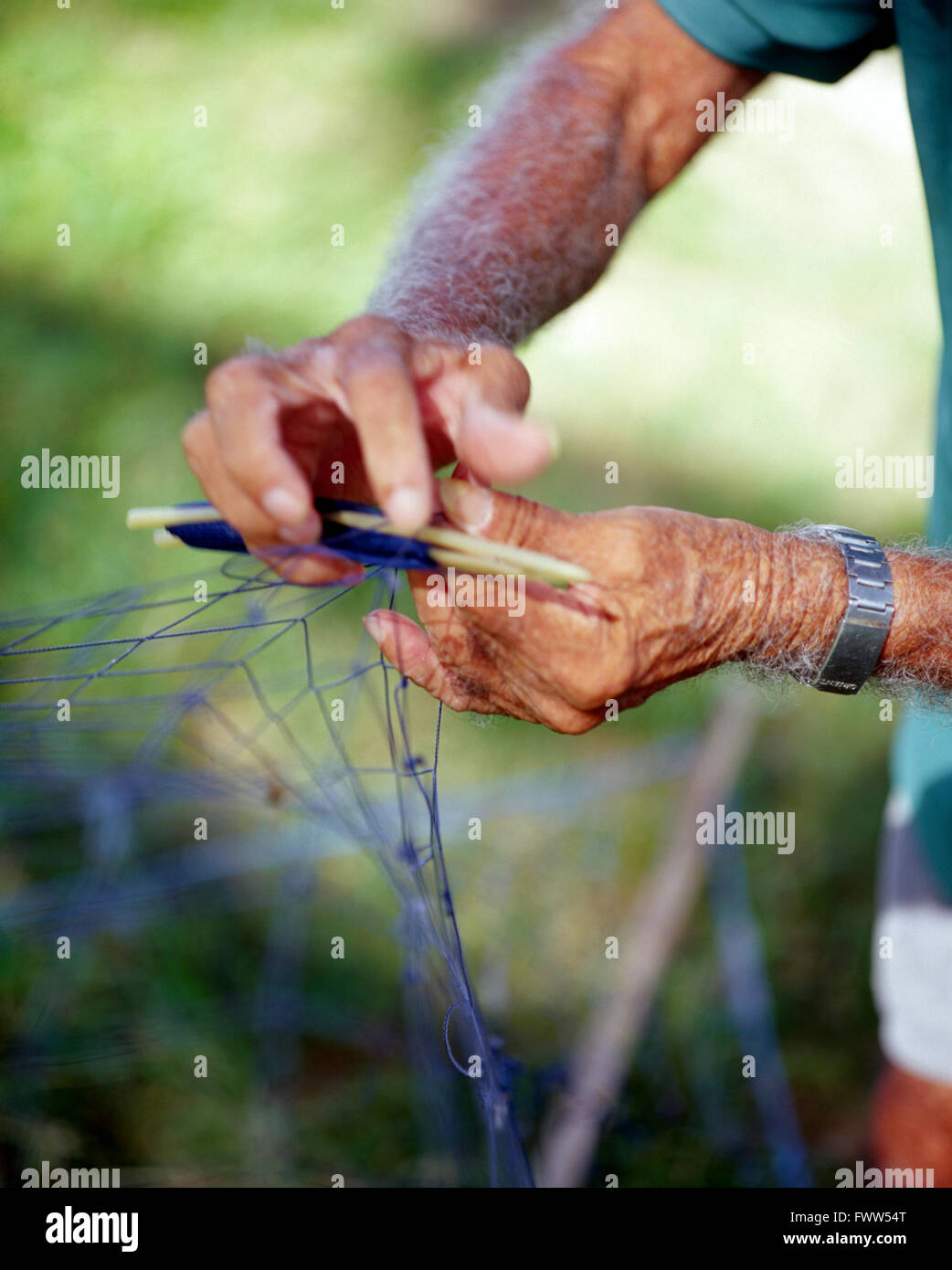 Old fisherman fixing fishing net, net repair Stock Photo - Alamy