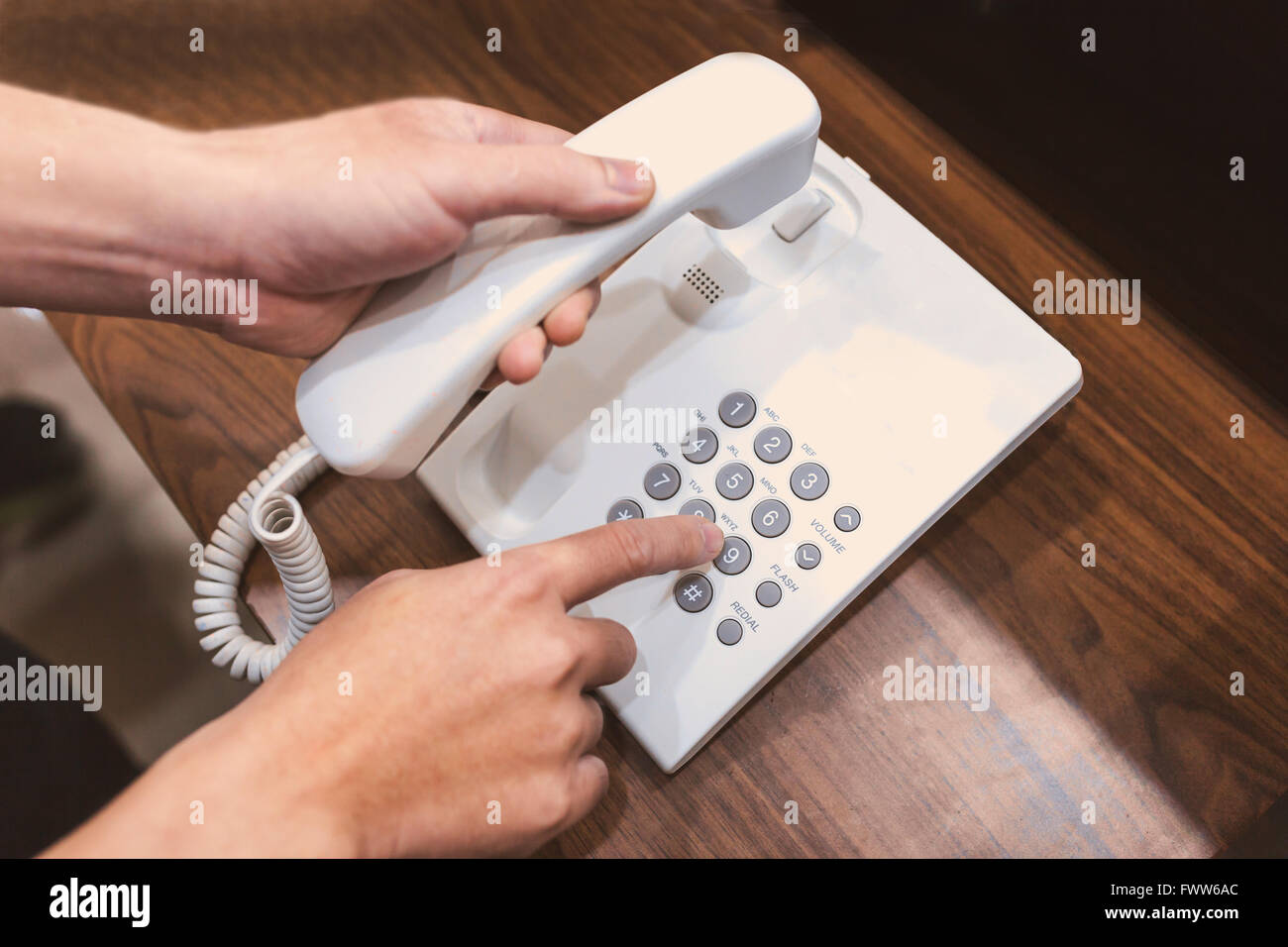 Human hands holding telephone handle and dialing on wooden table Stock ...