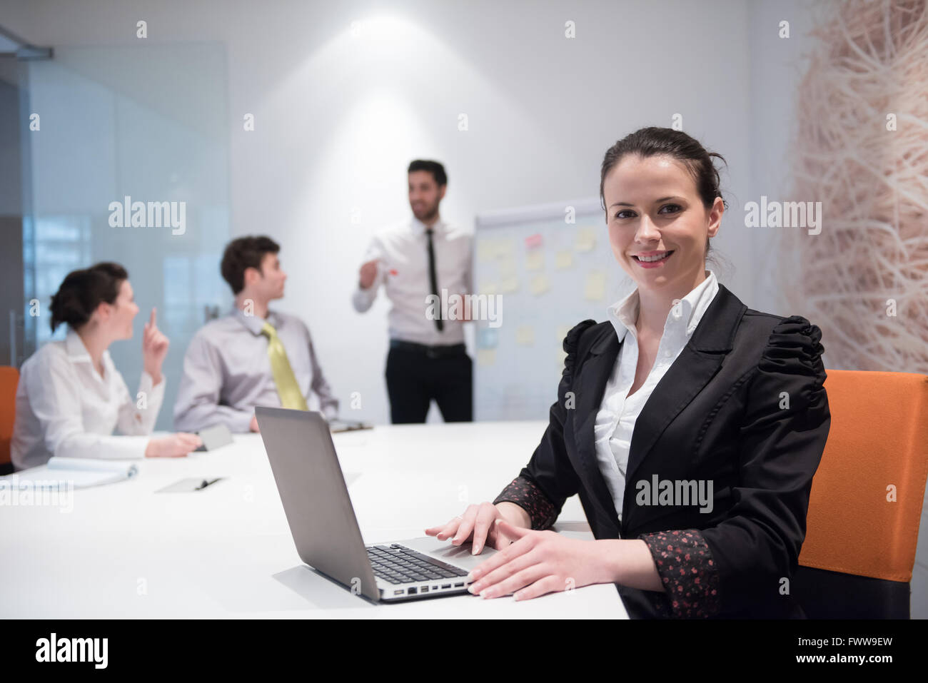 young business woman on meeting usineg laptop computer, blured group of ...