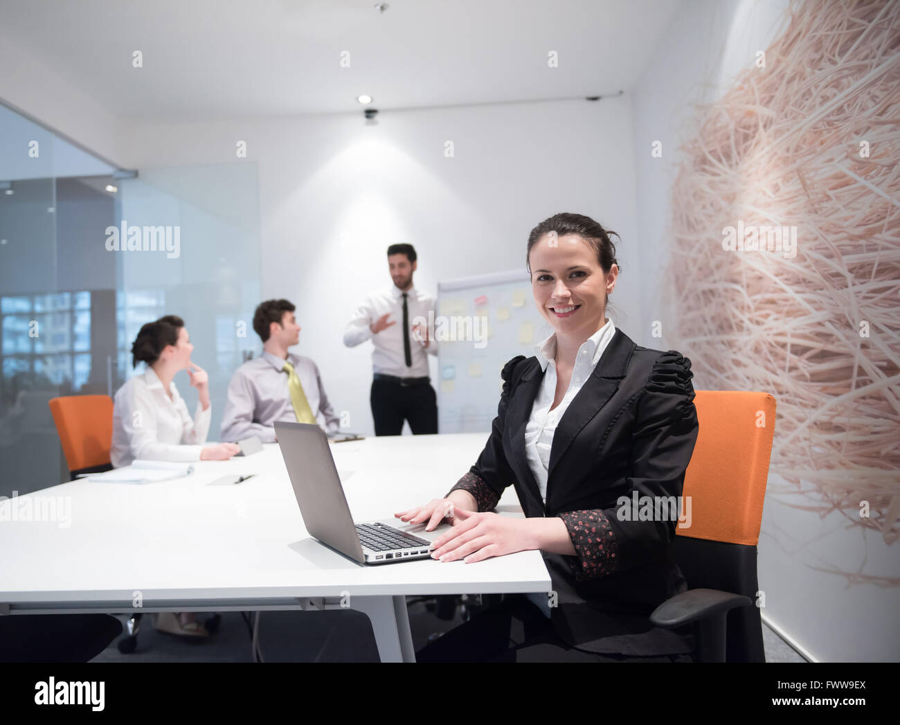 young business woman on meeting usineg laptop computer, blured group of ...