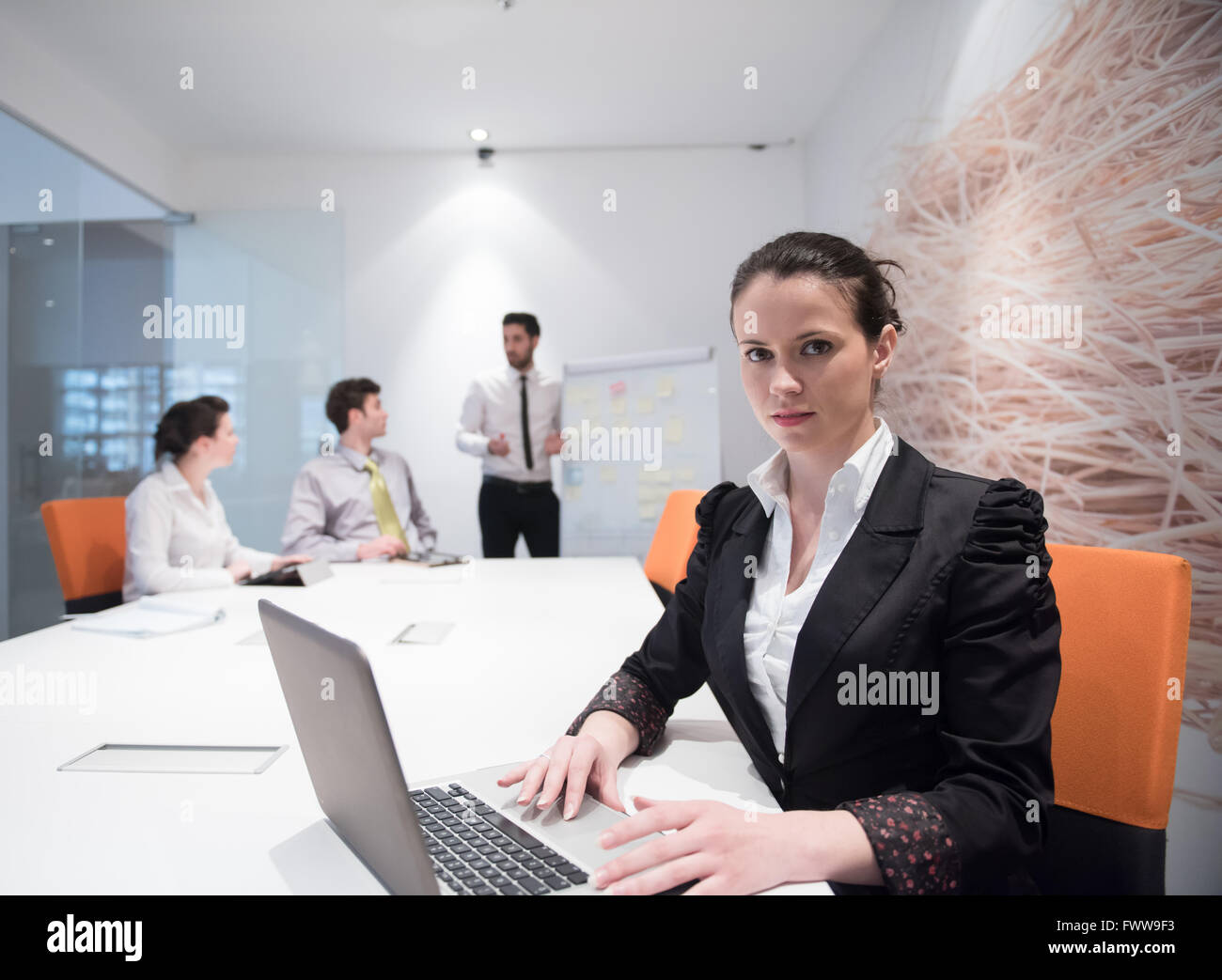 young business woman on meeting usineg laptop computer, blured group of ...
