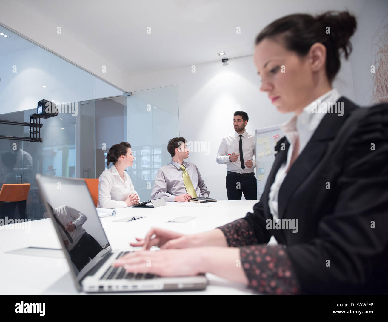 young business woman on meeting usineg laptop computer, blured group of ...