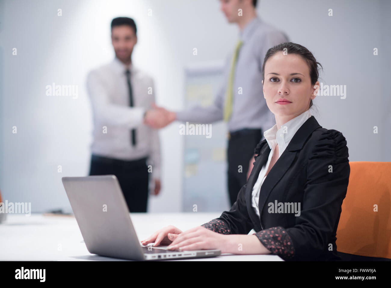 young business woman on meeting usineg laptop computer, blured group of ...