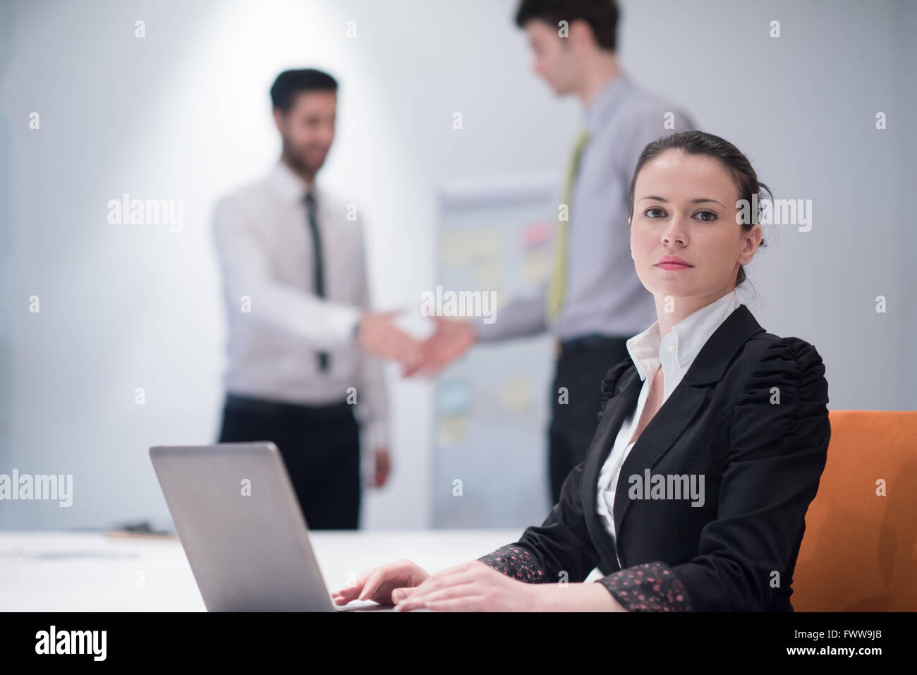young business woman on meeting usineg laptop computer, blured group of ...