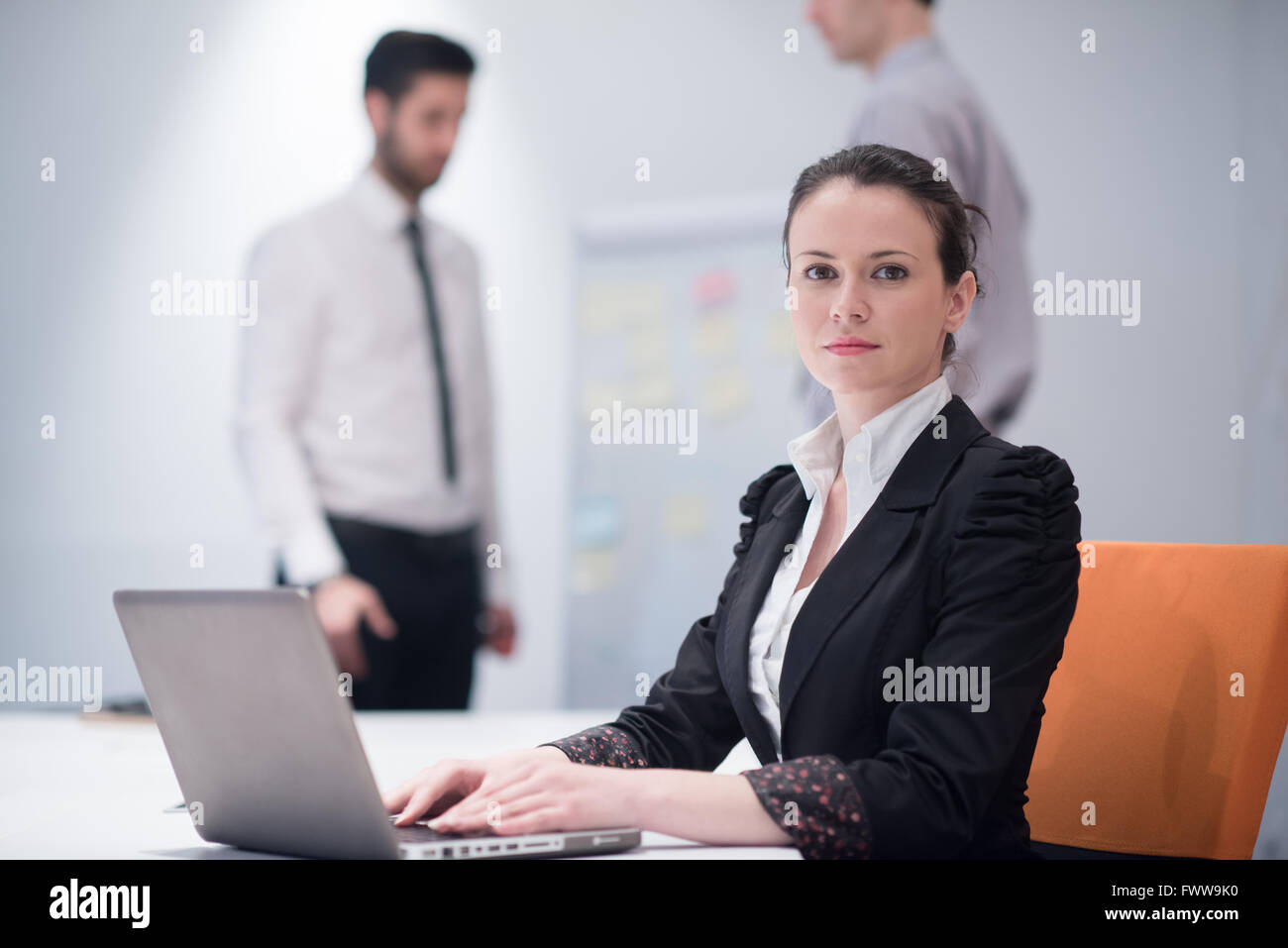 young business woman on meeting usineg laptop computer, blured group of ...
