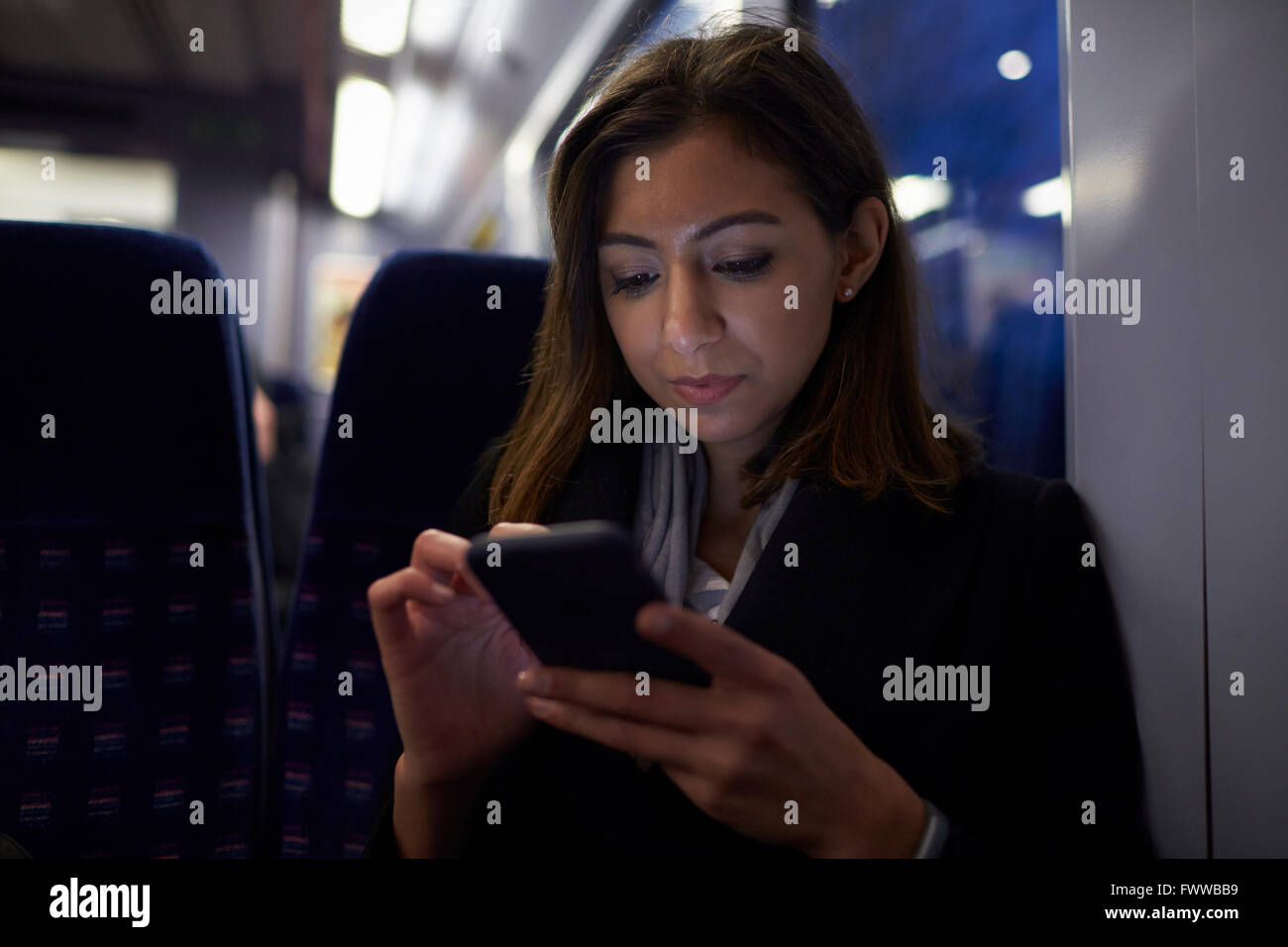 Woman Sitting In Train Carriage Sending Text Message Stock Photo - Alamy