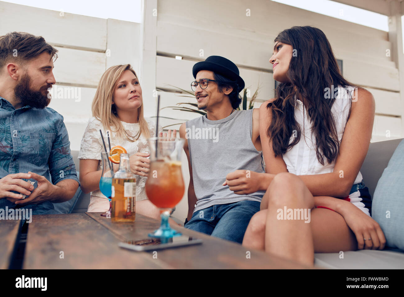 Group of young people sitting around a table chatting. Young friends ...
