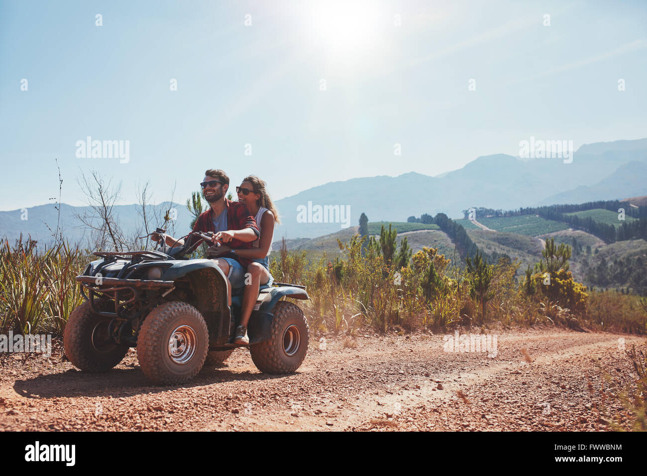 Loving young couple enjoying a quad bike ride in countryside. Couple ...