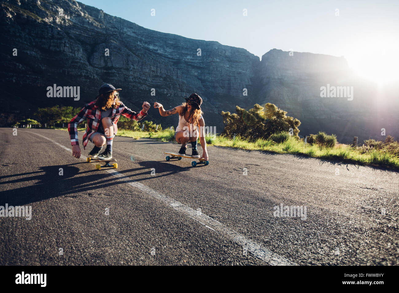 Best friends having fun with skateboard on open road. Young man and ...