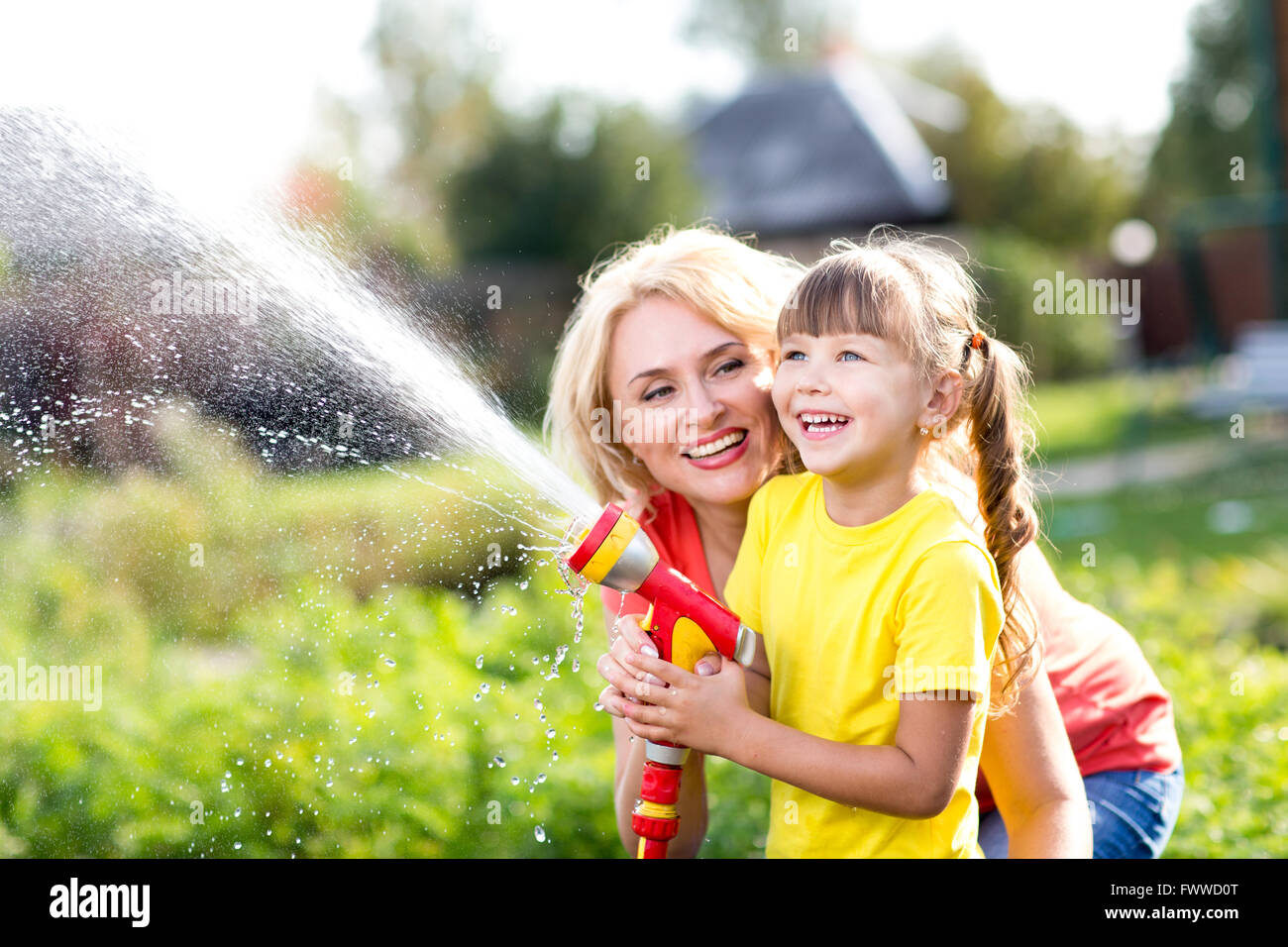 Little gardener girl with mother watering on lawn near house Stock ...