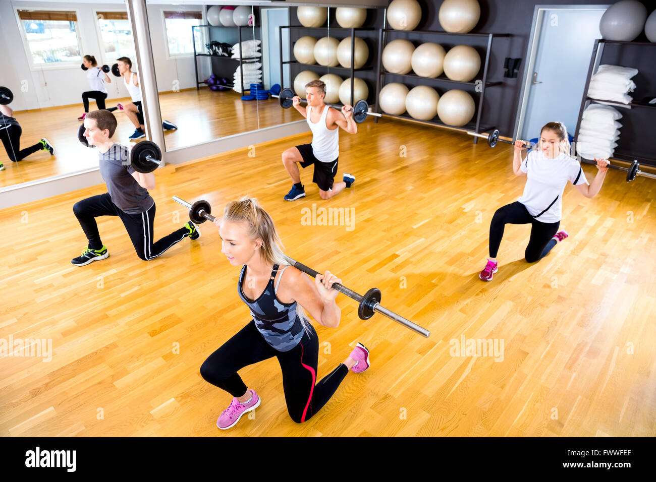 Focused team doing split squats with weights at fitness gym Stock Photo ...