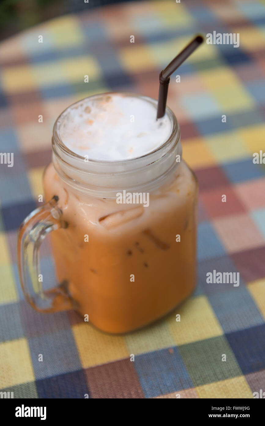 Ice milk tea with straw in cube glass with handle in selective focus ...