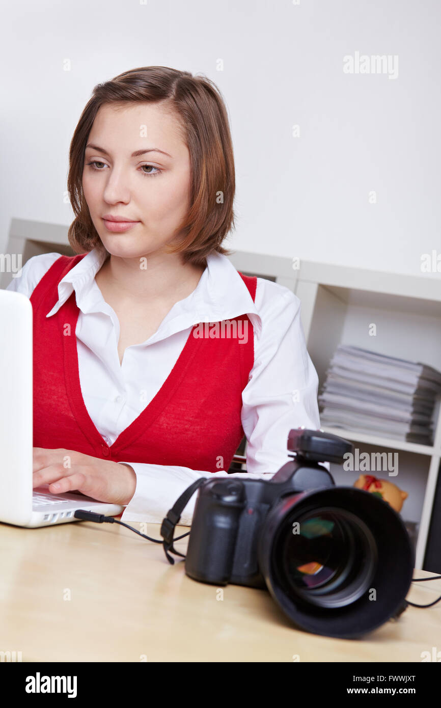 Professional female photographer transfering images from DSLR camera to ...